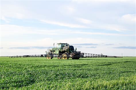 미세 하 게 분산 된 비료 살포 장치 트랙터 일몰 배경에 트랙터입니다 높은 바퀴 트랙터 젊은 밀에 비료를 만들고 있다 미세 하