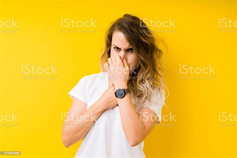노란색 배경 뭔가 냄새 나 고 역 겨 운 냄새 참을 냄새 코에 손가락으로 잡고 숨을 젊은 아름 다운 금발 여자 나쁜 냄새 개념입니다 곱슬 머리에 대한 스톡 사진 및 기타