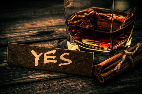 황마 로프와 나무 판자로 묶인 계피 막대기가 달린 브랜디 유리는 오래된 나무 테이블에 Yes라는 비문입니다 0명에 대한 스톡