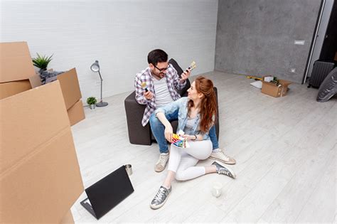 몇 푼된 상자와 새로운 평면에 앉아 하 고 컬러 팔레트를 보고 그는 페인트 붓을 들고는 하는 동안 벽을 페인트 하는 색상 선택 2명에 대한 스톡 사진 및 기타 이미지