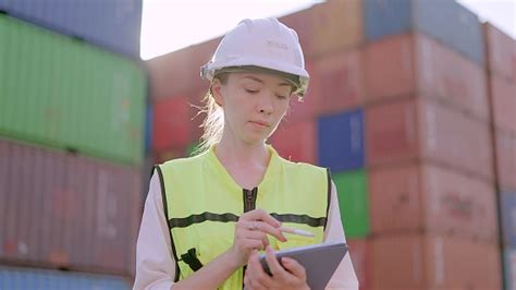 안전 조끼 안전모를 착용하고 디지털 태블릿을 사용하여 화물 컨테이너를 점검하고 적재장에서 운송 계획에 따라 화물 및 컨테이너 트럭의 적재를 제어하는 전문 여성 작업자 사람