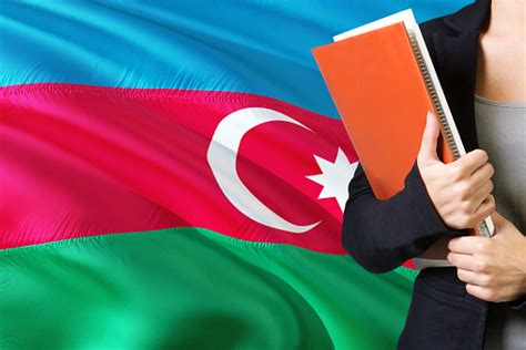 아제르바이잔어 언어 개념을 학습 배경에 아제르바이잔 국기와 함께 서 있는 젊은 여자 책을 들고 교사 오렌지 빈 책 표지 교사 교육 관련 직업에 대한 스톡 사진 및 기타