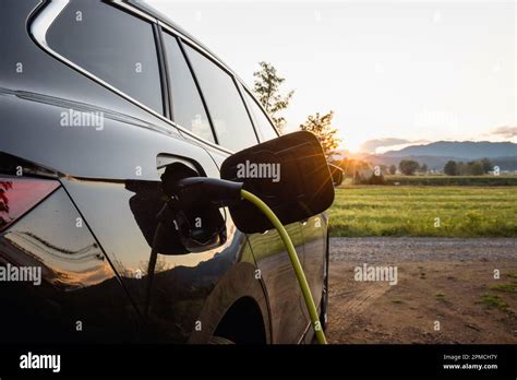 Power Cable Connected With A Charger Plugged Into A Black Electric Car