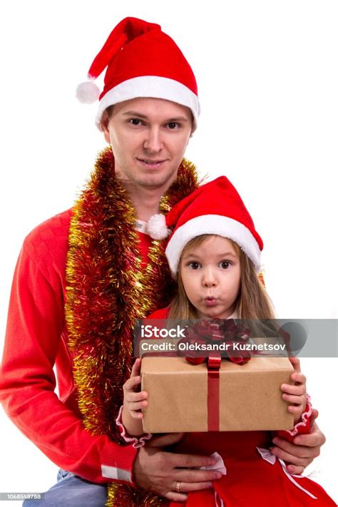 가족 아늑한 크리스마스 시간입니다 딸은 선물 상자를 들고 아버지 무릎에 앉아 있다 딸 그리고 아버지 입고 산타 모자와 반짝이 목 세로 이미지 12월에 대한 스톡 사진 및