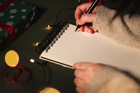 크리스마스를 위해 장식 된 방에서 산타에게 편지를 쓰는 여자 크리스마스 편지입니다 복사 공간이 있는 빈 페이지가 있는 손과 공책 디자인을 위한 모형 12월에 대한 스톡 사진