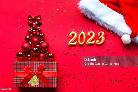 유리 공으로 만든 크리스마스 트리와 골드 별 스팽글과 빨간색 배경에 촛불에서 숫자 2023 크리스마스 배경 새해 산타 모자와