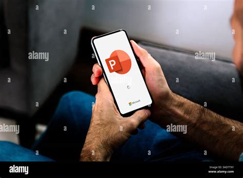 Man Using A Mobile Phone Displaying Logo Of Microsoft Office PowerPoint On The Screen Power