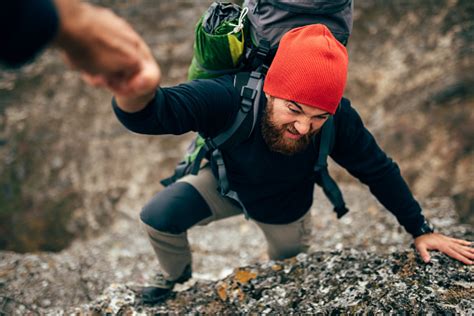 그의 여행 동안 여행자에 게 수염 남자 트레킹 및 등산의 수평 야외 촬영 산에서 젊은 관광 남성 하이킹을 돕는 친구의 손 여행 인물 스포츠 라이프 스타일 건강한 생활방식에