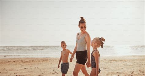 여름 방학 동안 모래 사장을 따라 걷는 동안 함께 손을 잡고 웃는 엄마와 그녀의 두 아이 사진 Unsplash의 어머니와 아들 이미지