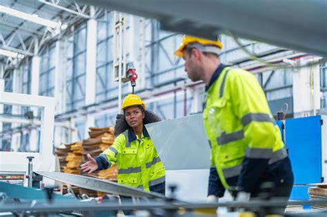 남성과 여성 기술공 엔지니어는 무거운 기계에 과정을 검사합니다 기계 공학 팀 생산 산업 제조 태블릿과 폴드를 들고 있는 작업자