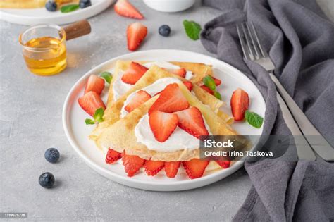 크림 치즈 신선한 딸기 꿀을 회색 콘크리트 배경의 흰색 접시에 크림 치즈 신선한 딸기 꿀이 있는 크레페 또는 얇은 팬케이크 공간을 복사합니다 팬케이크에 대한 스톡 사진 및