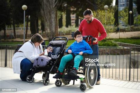 어머니와 아버지는 휠체어를 타고 아기와 장애인 아들과 함께 공원에서 가족의 날을 즐기고 있습니다 장애인에 대한 스톡 사진 및 기타 이미지 Istock