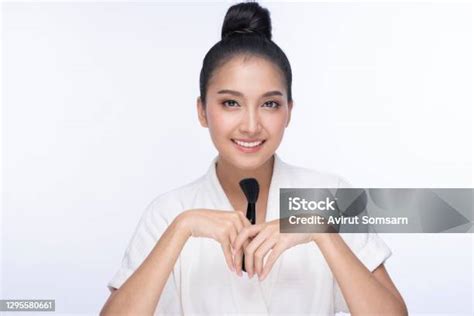 메이크업 브러쉬를 사용하여 얼굴에 마른 화장품 파운데이션을 적용한 여성의 초상화 메이크업 브러쉬를 손에 들고 깨끗한 피부로