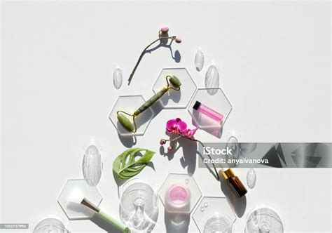 몬스터 잎 난초 꽃과 유리 Baubles 비취 돌 얼굴 롤러 항아리에 핑크 보습 제 크림 햇빛 긴 그림자 아름다움 치료 웰빙 플랫 누워 에 떨어져 서 화이트 배경 0명에