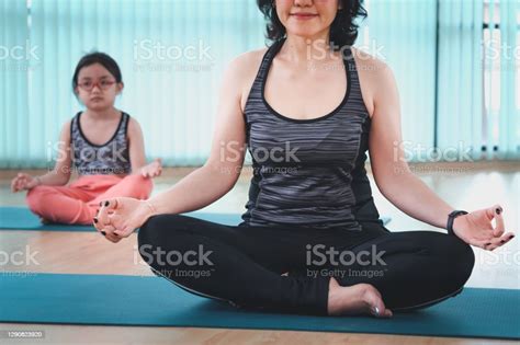 함께 실내 스튜디오에서 요가 운동을하는 어머니와 딸 함께 서 요가를 연습하고 영웅 포즈를하고 휴식 호흡 명상 운동과 운동을하고 그녀의 몸을 돌보는 운동 명상하기에 대한 스톡