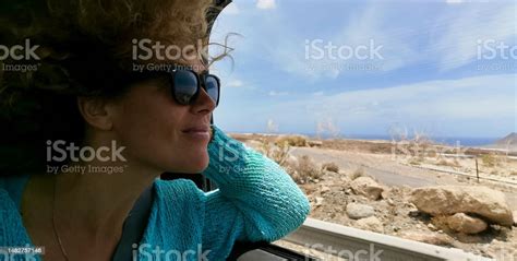 젊은 여자는 여행 수송 활동 중에 차 안에서 승객을 미소 짓는다 한 여성이 차 안에 앉아 창밖의 경치를 바라보며 여행을 즐기고 있다 여행자의 개념 경관에 대한 스톡 사진 및