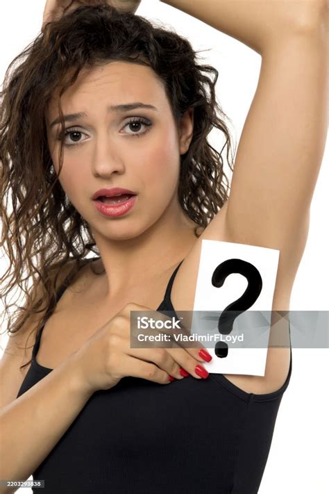 어리둥절한 표정을 짓고 물음표가 있는 카드를 들고 있는 젊은 여자 겨드랑이 제모 개념 스킨 케어의 불확실성을 보여주는 흰색