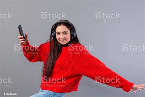 빨간 스웨터에 긍정적 인 여자 갈색 머리는 회색에 고립 된 헤드폰에서 스마트 폰에서 음악을 듣습니다 Mp3 플레이어에 대한 스톡 사진 및 기타 이미지 Istock