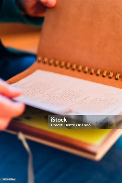 나선형 제본이 있는 노트북의 손으로 페이지를 넘기는 클로즈업 텍스트와 다채로운 페이지를 특징으로 하며 캐주얼한 환경에서 학습