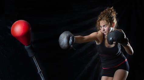 아름 다운 여성 펀칭 A 복싱 체육관에서 권투 장갑 가방 스포츠 피트 니스에 대 한 개념입니다 킥복싱과 싸움 스포츠 개념입니다 어두운 배경입니다 텍스트 복사 공간에 대 한