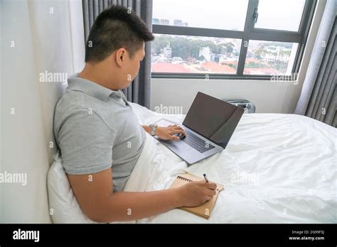 Using Laptop And Writing Notes In Bedroom Stock Photo Alamy