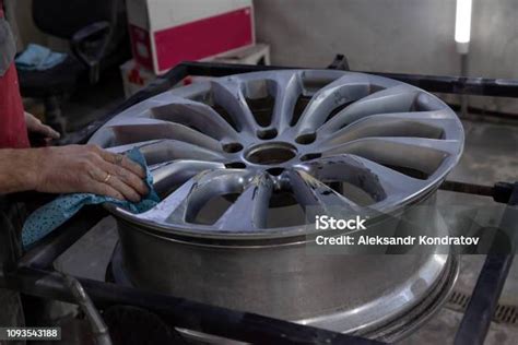 마스터 바디 수리 남자 워크숍에서 이후의 그림 청소 및 수평 연마 재료의 도움으로 휠 자동차의 알루미늄 바퀴의 표면 준비 작업은 바퀴에 대한 스톡 사진 및 기타 이미지