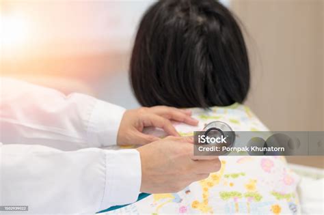 흰색 유니폼 가운을 입은 전문 일반 의료 소아과 의사가 청진기를 가진 아시아 어린이 환자의 폐와 심장 소리를 듣는다 의사는 병원에서 아시아 아이 여성과 상담을 검진한다