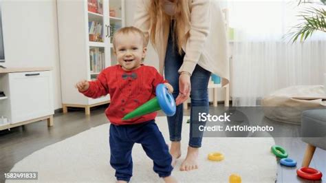 엄마와 함께 첫 발걸음을 내딛고 카메라를 향해 걸어가는 귀여운 아기 아기 발달 가족 게임 첫 걸음 내딛기 부모 역할 및 보살핌 18 23 개월에 대한 스톡 사진 및 기타