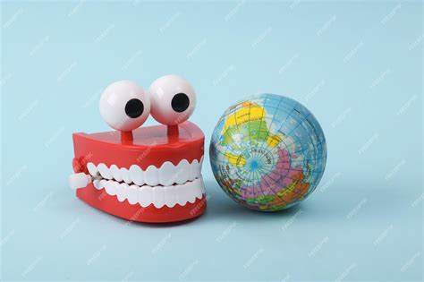 Premium Photo Funny Toy Clockwork Jumping Teeth With Eyes And Globe On Blue Background World