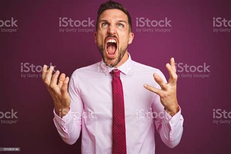 우아한 셔츠를 입고 보라색 고립 된 배경에 넥타이를 매고 미친 듯이 외치고 공격적인 표정과 팔을 들고 고함을 지르는 젊은 사업가 좌절 개념입니다 감정에 대한 스톡 사진 및