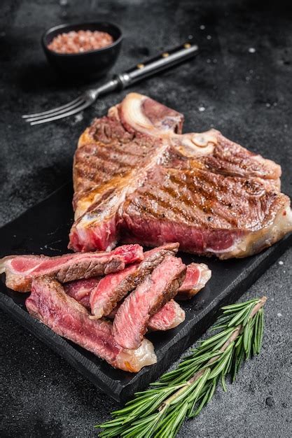 T 뼈 구이 쇠고기 고기 스테이크 요리 대리석 보드 검은 배경 상위 뷰에 포터 하우스 프리미엄 사진
