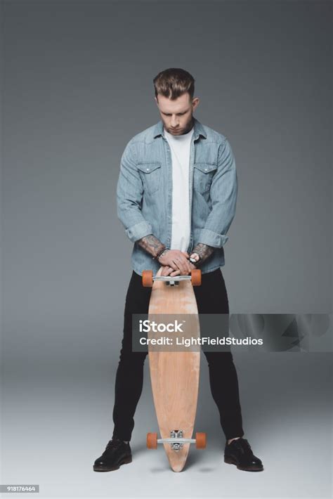 회색에 스케이트 보드와 함께 서 있는 잘생긴 젊은 문신된 남자의 전체 보기 남자에 대한 스톡 사진 및 기타 이미지 남자 문신 전신 Istock