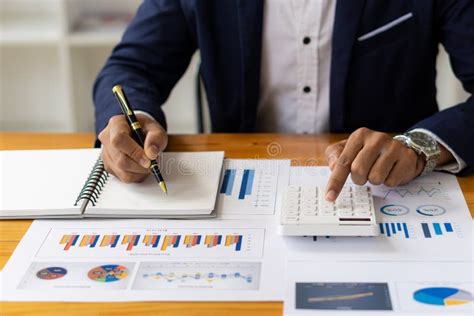 Businessman Holding Pen While Reading Statistics Graph On His Desk Office Work Concept Analysis