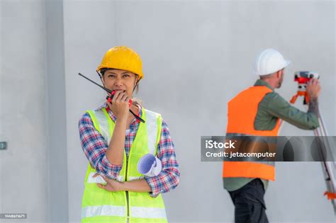 건설 현장의 수평 및 수직 평면의 각도를 측정하기 위해 테오돌라이트 측량 광학 기기를 사용하는 건설 작업자 엔지니어 와 건축가 측량 옆에 태블릿을 사용하여 2명에 대한 스톡