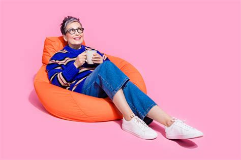 연금 수령자 여자 콩 주머니 커피 모습 빈 공간을 입은 전신 사진 분홍색 배경 고립 된 세련된 파란색 줄무늬 옷 50 54세에 대한 스톡 사진 및 기타 이미지 Istock