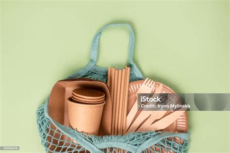 친환경 식기의 최고 전망 복사 공간이있는 밝은 녹색 배경에 파란색 면 그물 가방에 나무 칼붙이와 크래프트 종이 식품 컵과 용기 길거리 음식은 종이 포장을 빼앗습니다 0명에