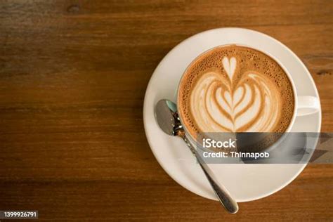 상단 보기에 나무 책상에 컵 머그잔에 라떼 아트 밀크 폼 뜨거운 커피 라떼 아침 식사로 카페에서 커피 숍에서 비즈니스 작업 개념