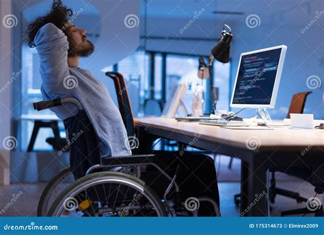Disabled Web Developer In The Wheelchair Works In The Office At The Computer While Performing In