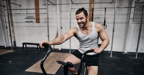 체육관에서 운동 세션 동안 고정식 자전거를 타고 땀을 흘리며 웃고 있는 운동복을 입은 청년 사진 Unsplash의 운동용 자전거 이미지