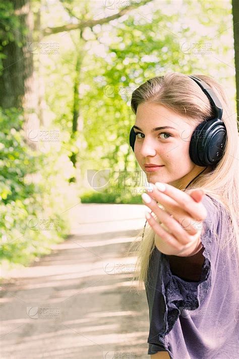 户外的年轻女孩戴着耳机，听音乐素材 花瓣网