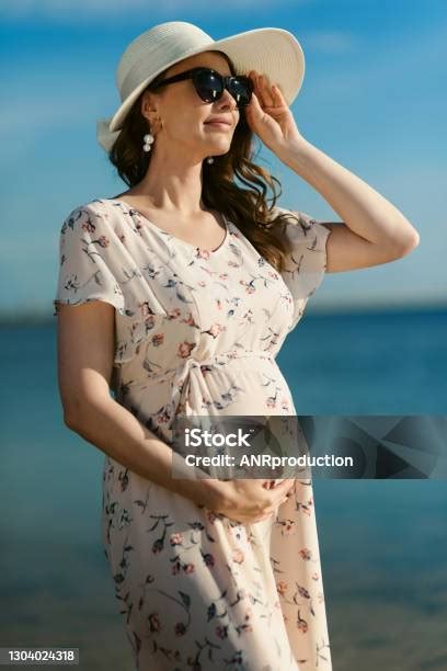 해변 바다 쪽에 흰색 드레스와 모자를 입은 매력적인 젊은 임산부 출산을 기다리는 임산부 임신의 세 번째 삼분기의 시작 건강한 생활방식에 대한 스톡 사진 및 기타 이미지