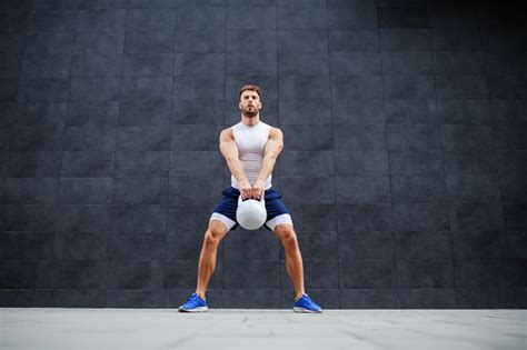반바지와 티셔츠에 강한 근육 잘 생긴 백인 남자 야외서 스윙 주전자 벨 배경은 회색 벽입니다 케틀벨에 대한 스톡 사진 및 기타 이미지 Istock