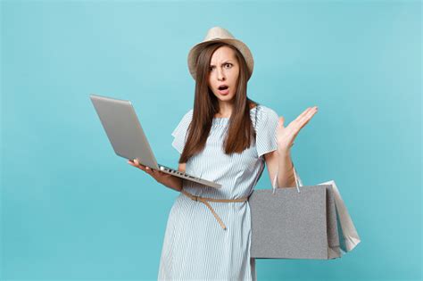 여름 드레스 온라인 쇼핑 후 구매와 패키지 가방을 들고 밀 짚 모자에에서 젊은 여자의 초상화 블루 파스텔 배경에 고립 된 노트북 Pc 컴퓨터를 사용 합니다 광고에 대 한