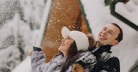 겨울 눈 덮인 산을 배경으로 나무 오두막에서 눈을 가지고 노는 세련된 커플 눈 속에서 재미 있고 웃는 행복한 즐거운 가족 함께 감동적인 재미있는 순간들 사진