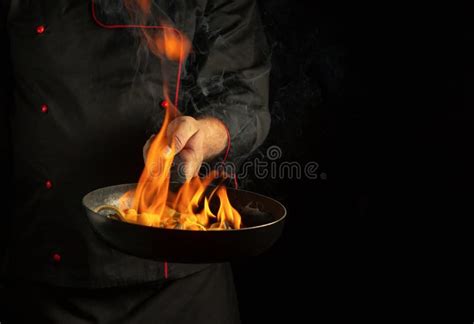 The Cook Preparing Delicious Dinner On A Burning Frying Pan With Flame
