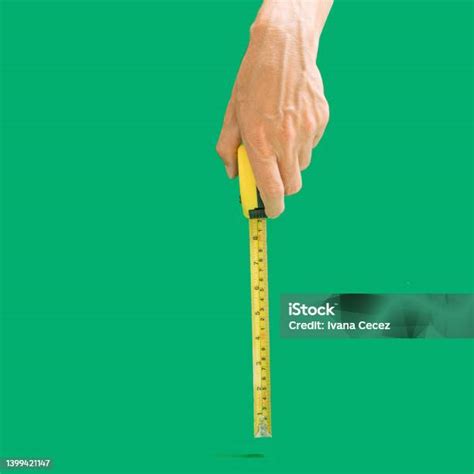 사람의 손은 길이를 측정하기 위해 줄자를 인치와 센티미터로 잡습니다 플라스틱 코팅 강철 블레이드 손 측정 녹색 배경 줄자에 대한