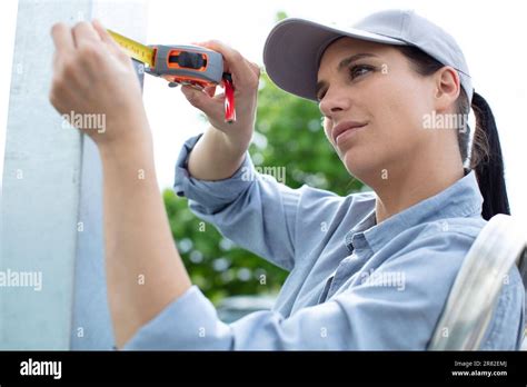 Woman On A Stepladder Using A Tape Measure Stock Photo Alamy