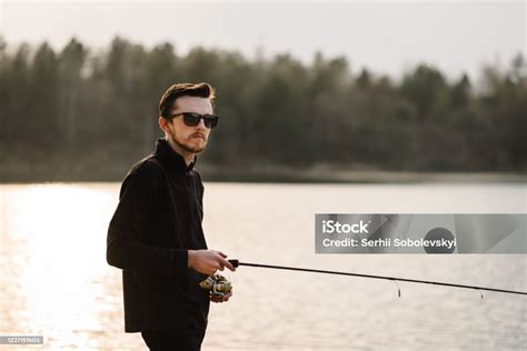Nelayan Dengan Batang Berputar Gulungan Di Tepi Sungai Manusia Menangkap Ikan Menarik Batang
