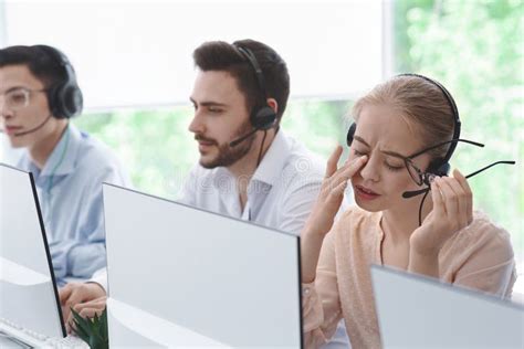 Overworked Hotline Operator In Front Of Computer Monitor And Her Busy Coworkers At Call Center