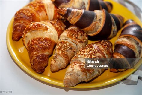 접시에 너트 부스러기가 든 초콜릿 크로와상 또는 크로와상 테이블에 아침 식사 커피를위한 달콤한 베이킹 디저트 달콤한 음식에 대한